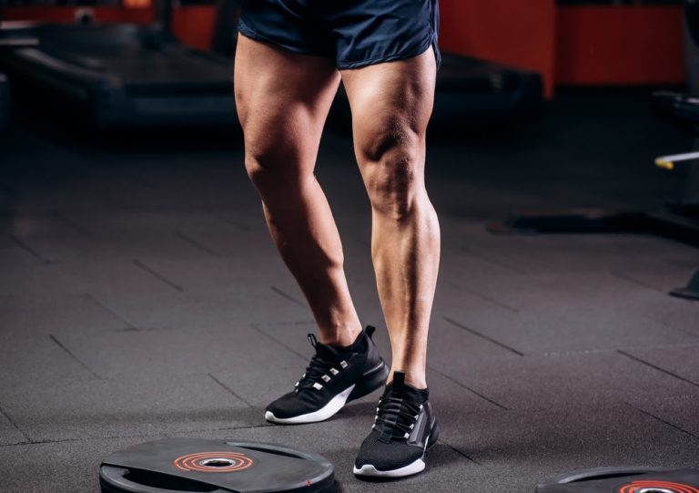 Man standing strong in the gym and flexing legs close up | Muscle Pursuits